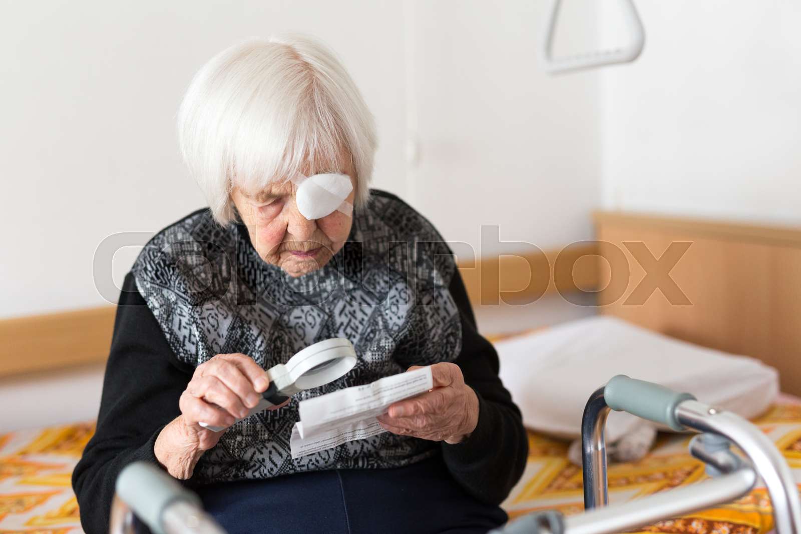 Visually impaired elderly 95 years old woman sitting at the bad trying ...