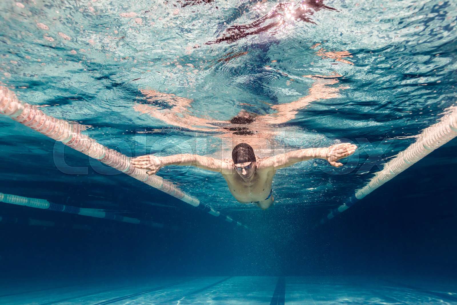 underwater picture of young swimmer in cap and goggles training in ...