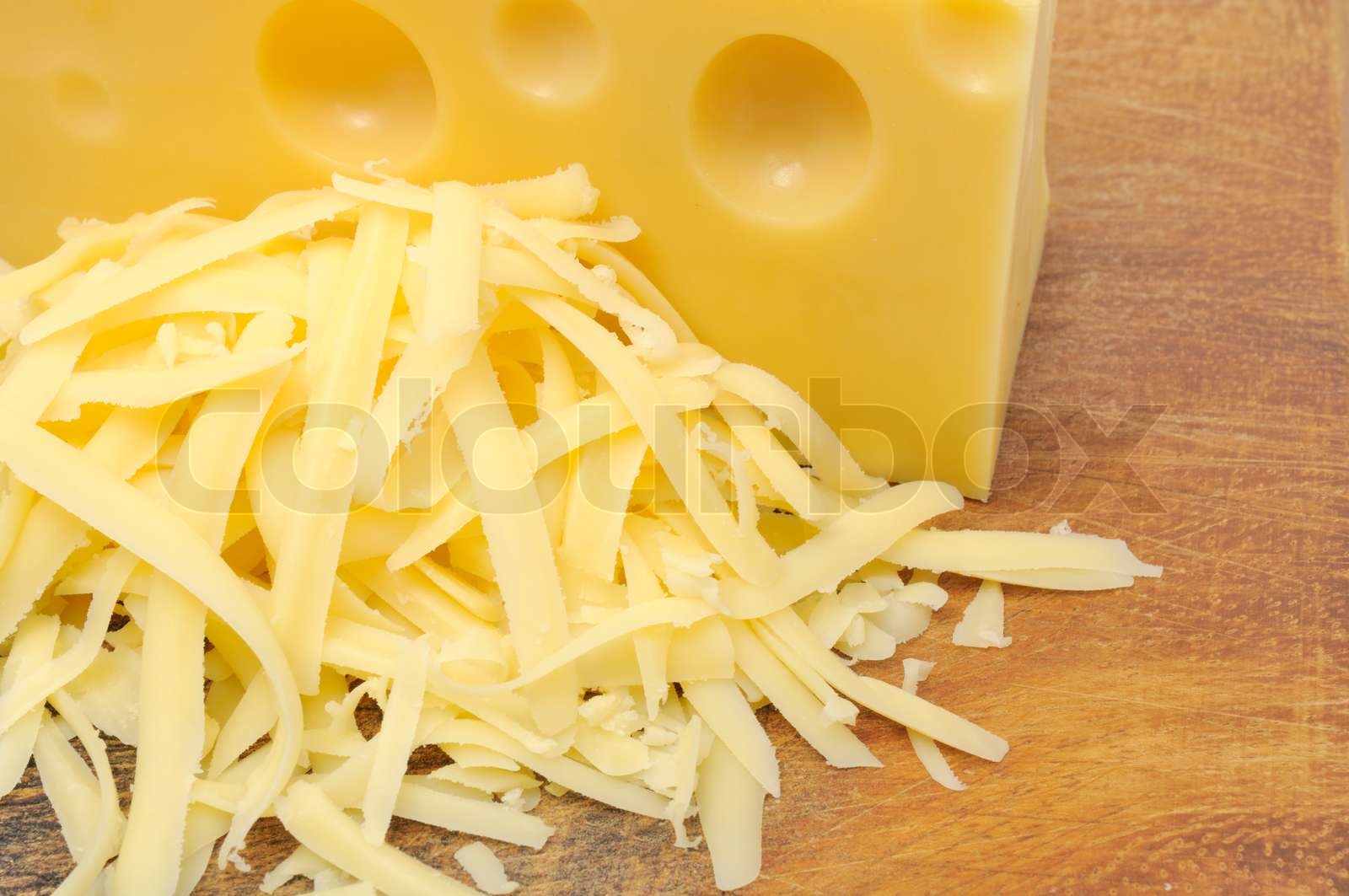 Pile of Grated Cheese and Chunk of Cheese on Wooden Chopping Board ...