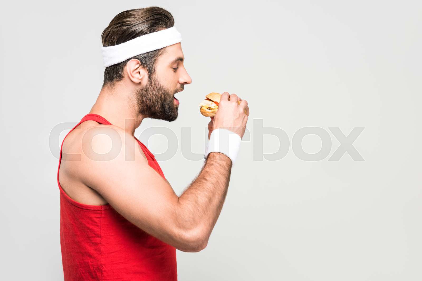 bearded sportsman eating hamburger, isolated on white | Stock image ...