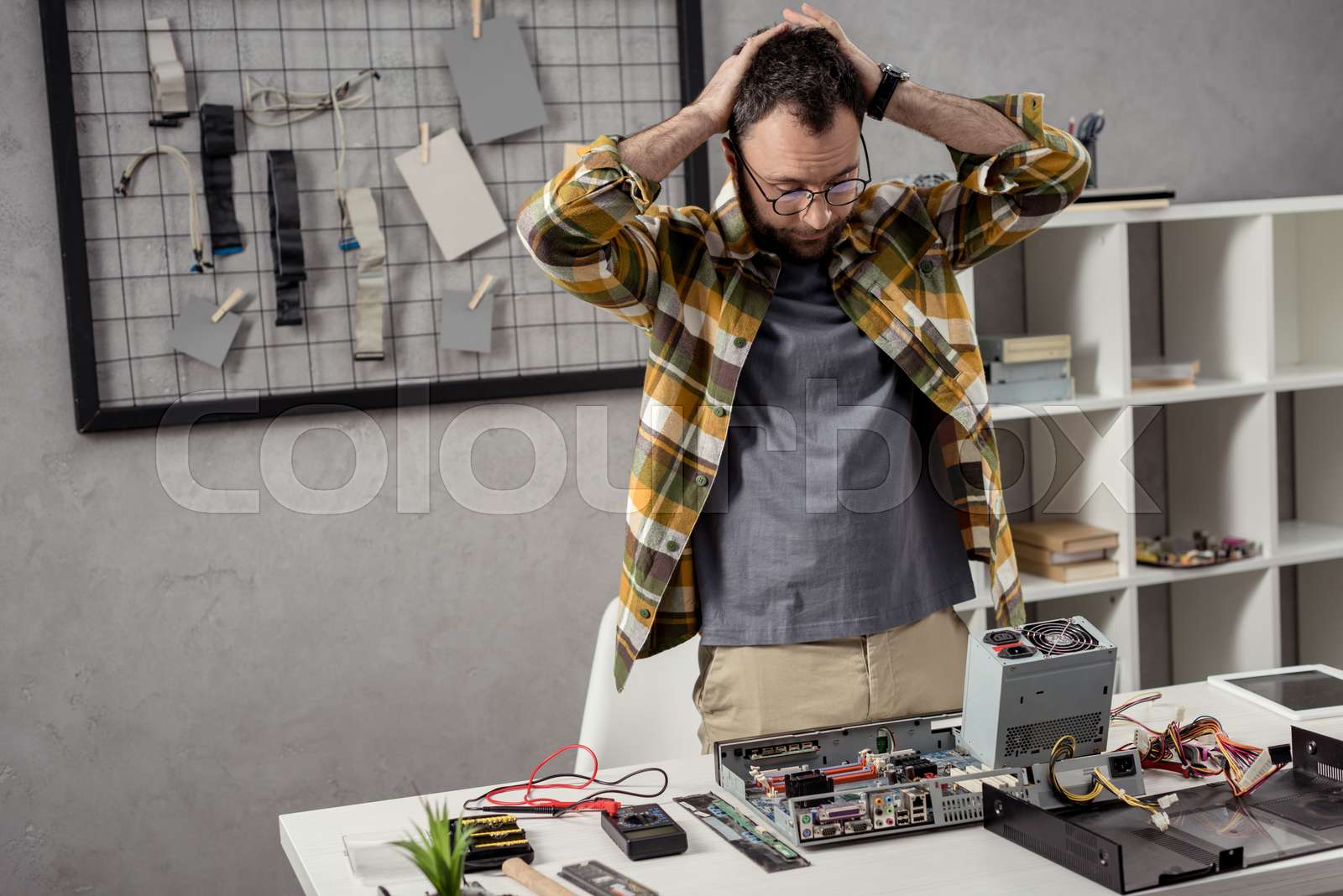 tired repairman looking down on broken computer | Stock image | Colourbox