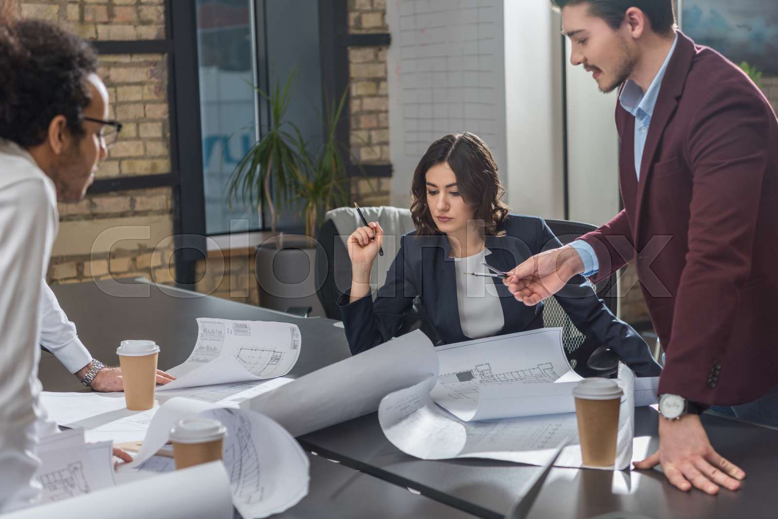 team of successful architects brainstorming on building plans | Stock ...