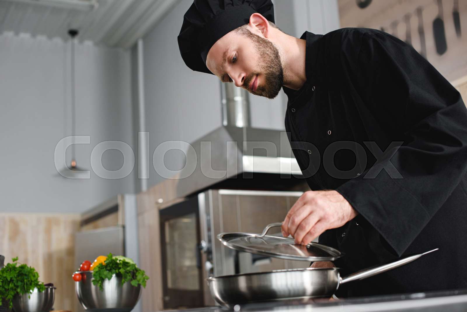 side view of handsome chef cooking with frying pan at restaurant ...