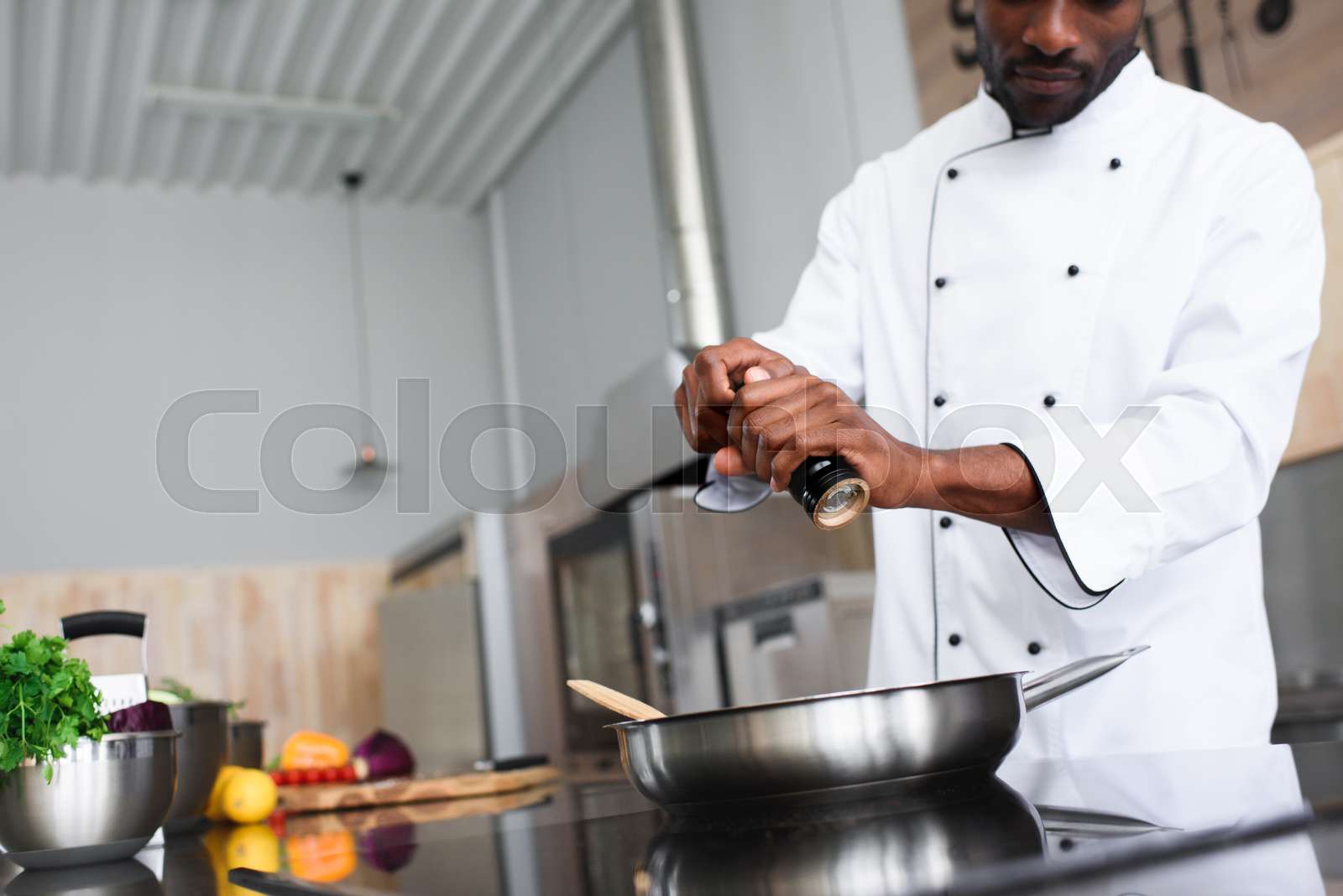 African american chef seasoning dish by kitchen stove | Stock image ...
