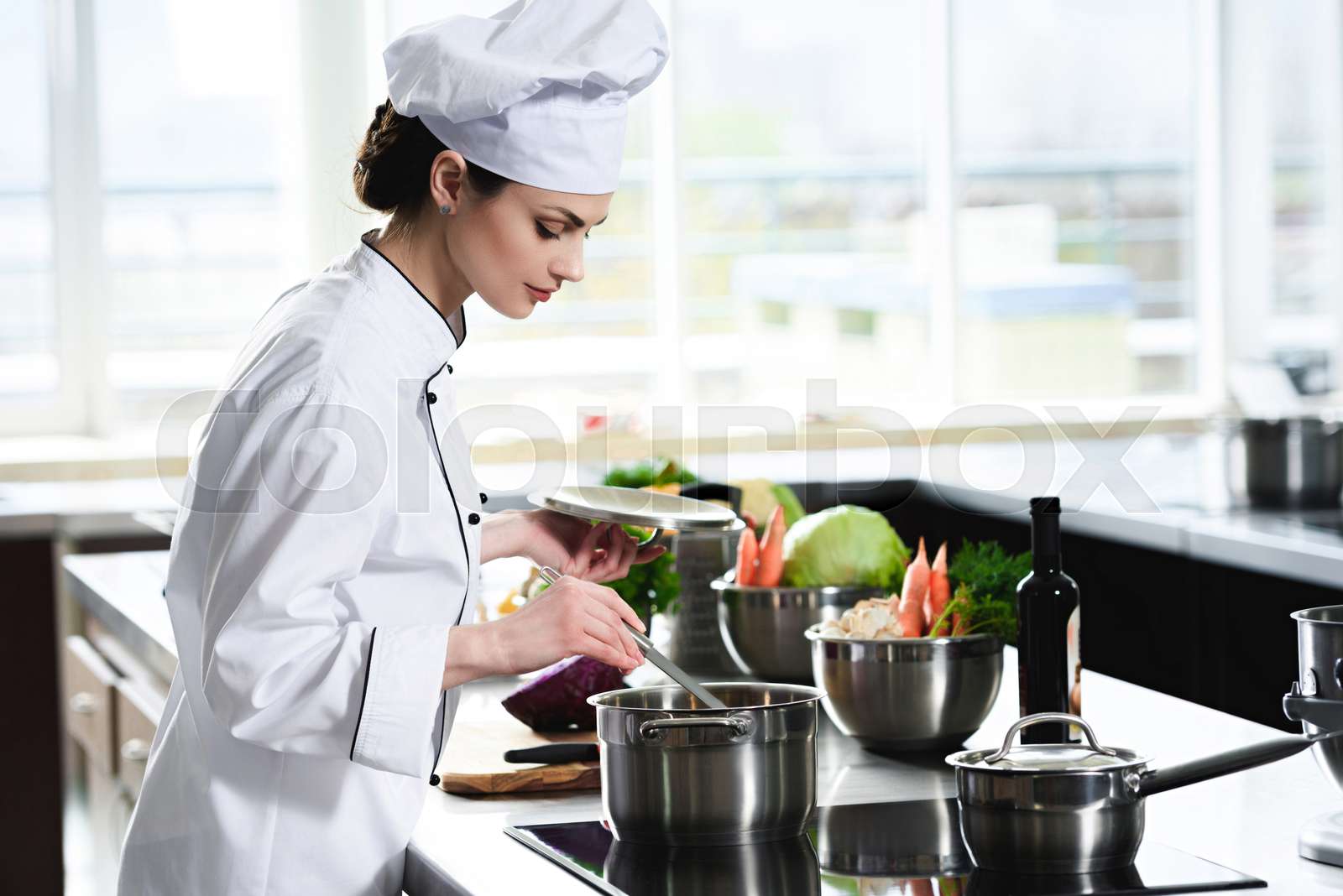 Woman chef cooking in pan on kitchen stove | Stock image | Colourbox