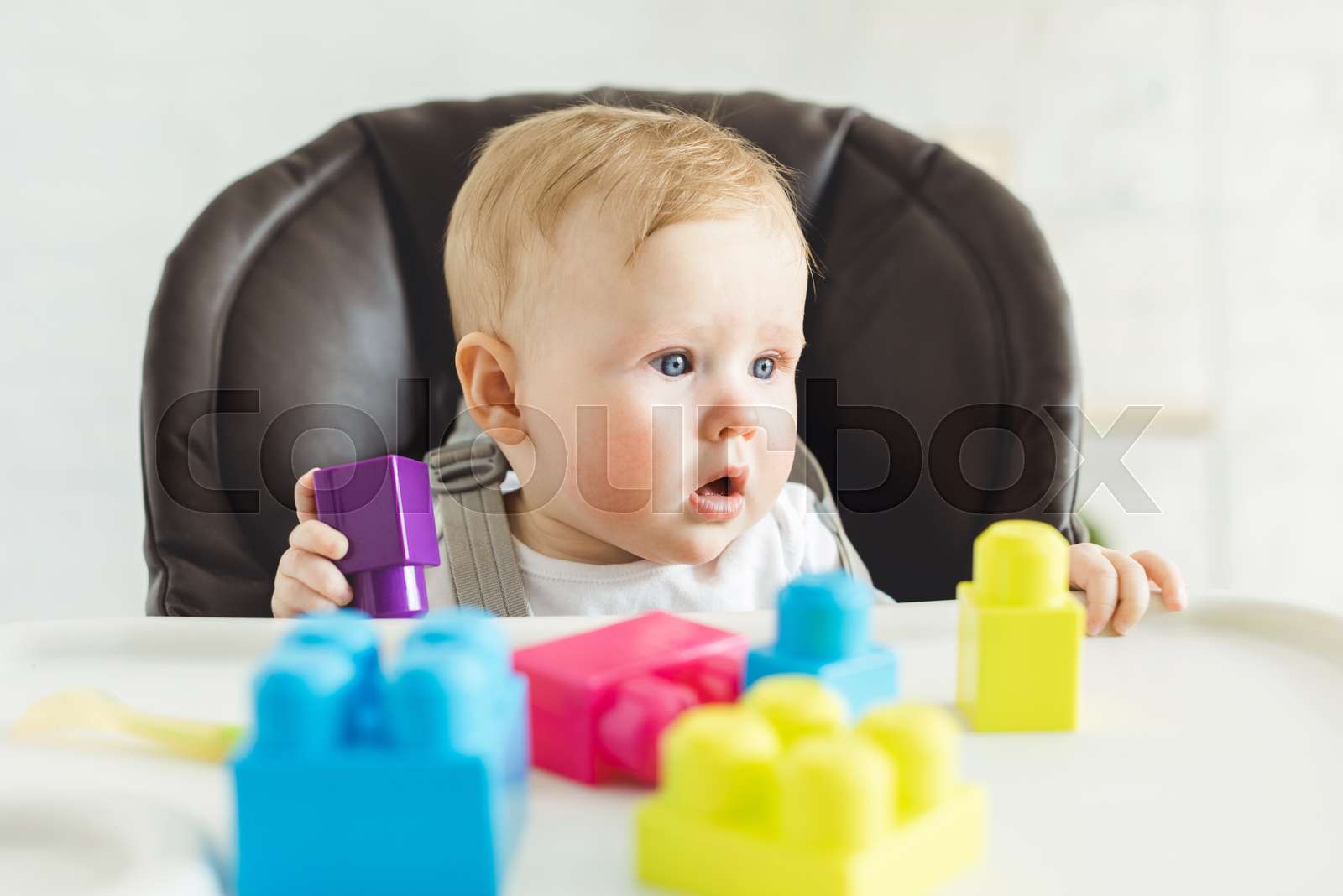 Adorable infant sititng in baby chair with plastic blocks | Stock image ...