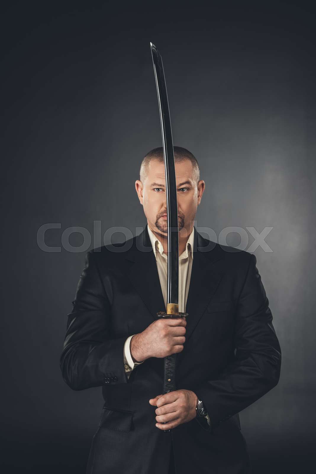 man in suit holding katana sword in front of his face on black | Stock ...
