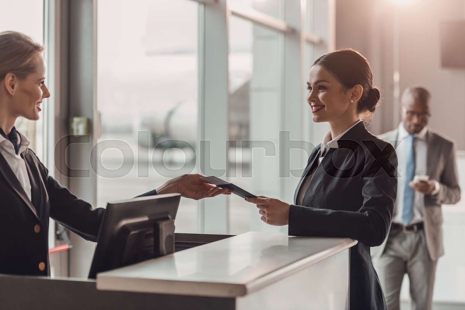 smiling young businesswoman giving passport and ticket to staff at ...