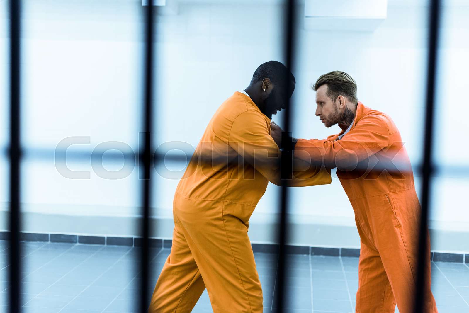 side view of multiethnic prisoners fighting behind prison bars | Stock ...