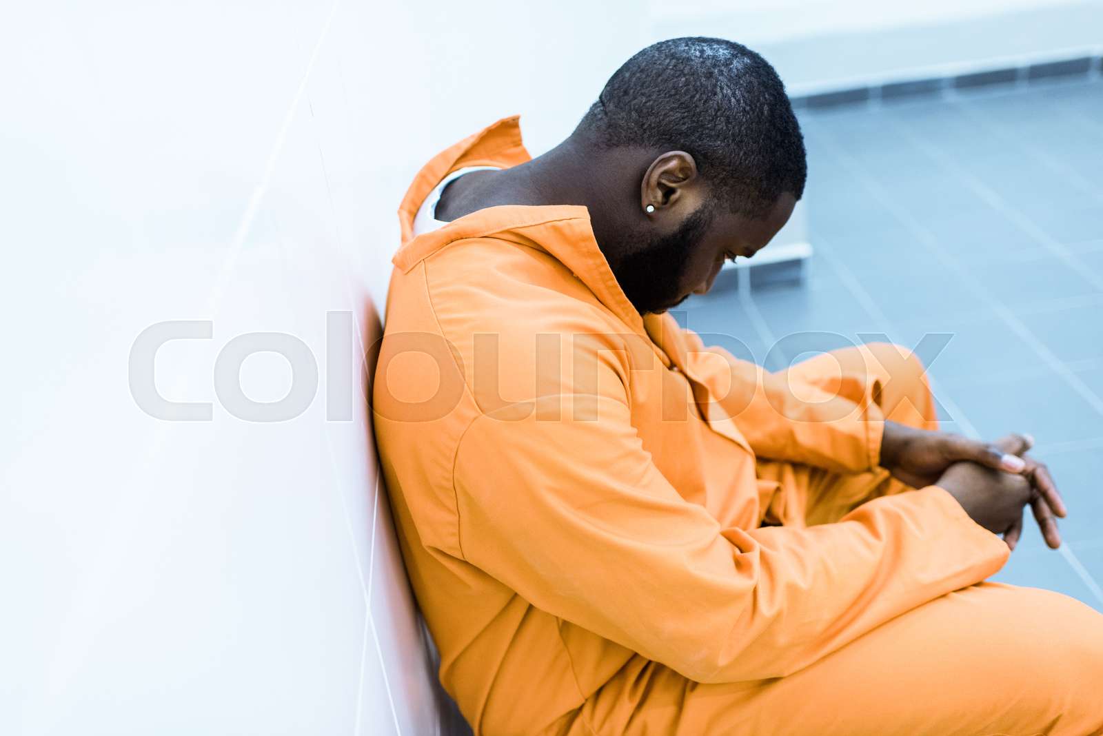 sad african american prisoner sitting on bench in prison cell | Stock ...