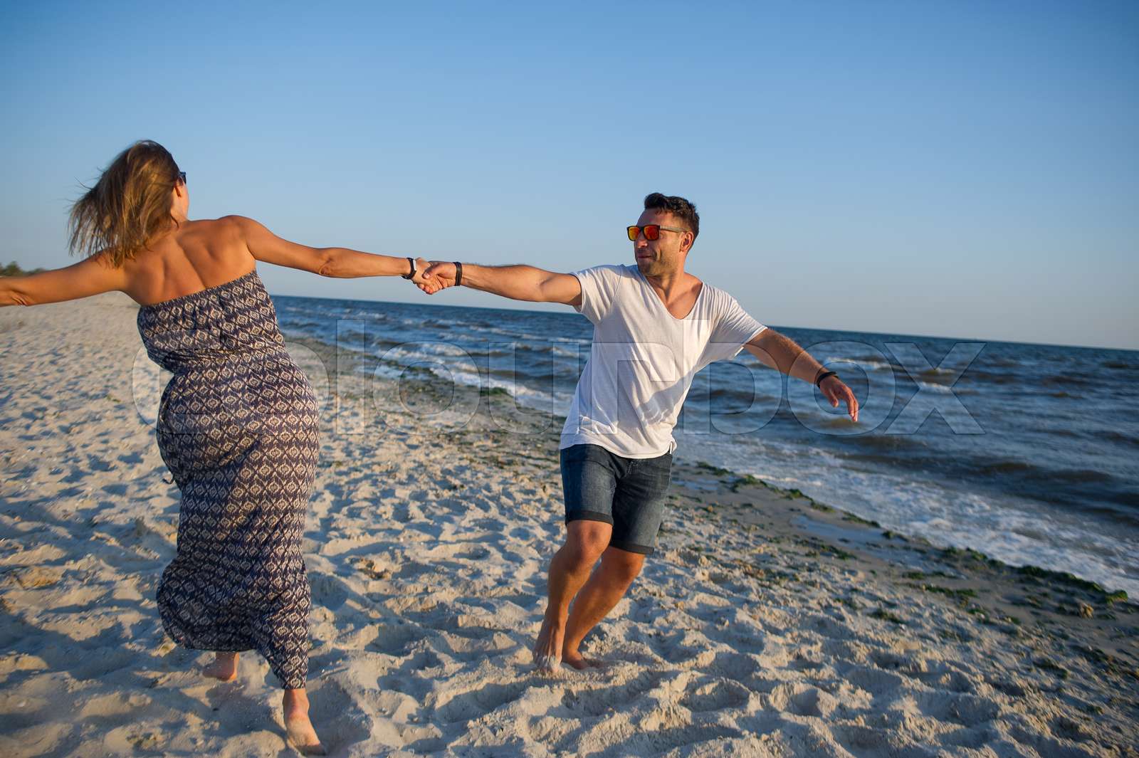Man and woman circling in the dance on the beach. | Stock image | Colourbox