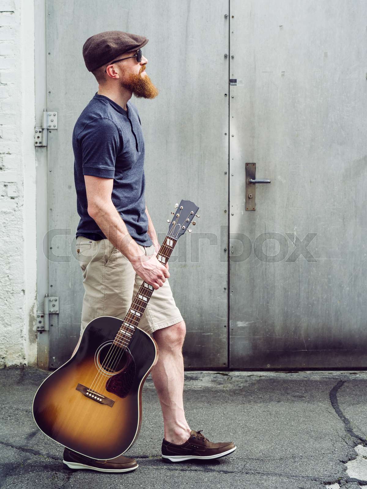 Bearded man walking with acoustic guitar | Stock image | Colourbox