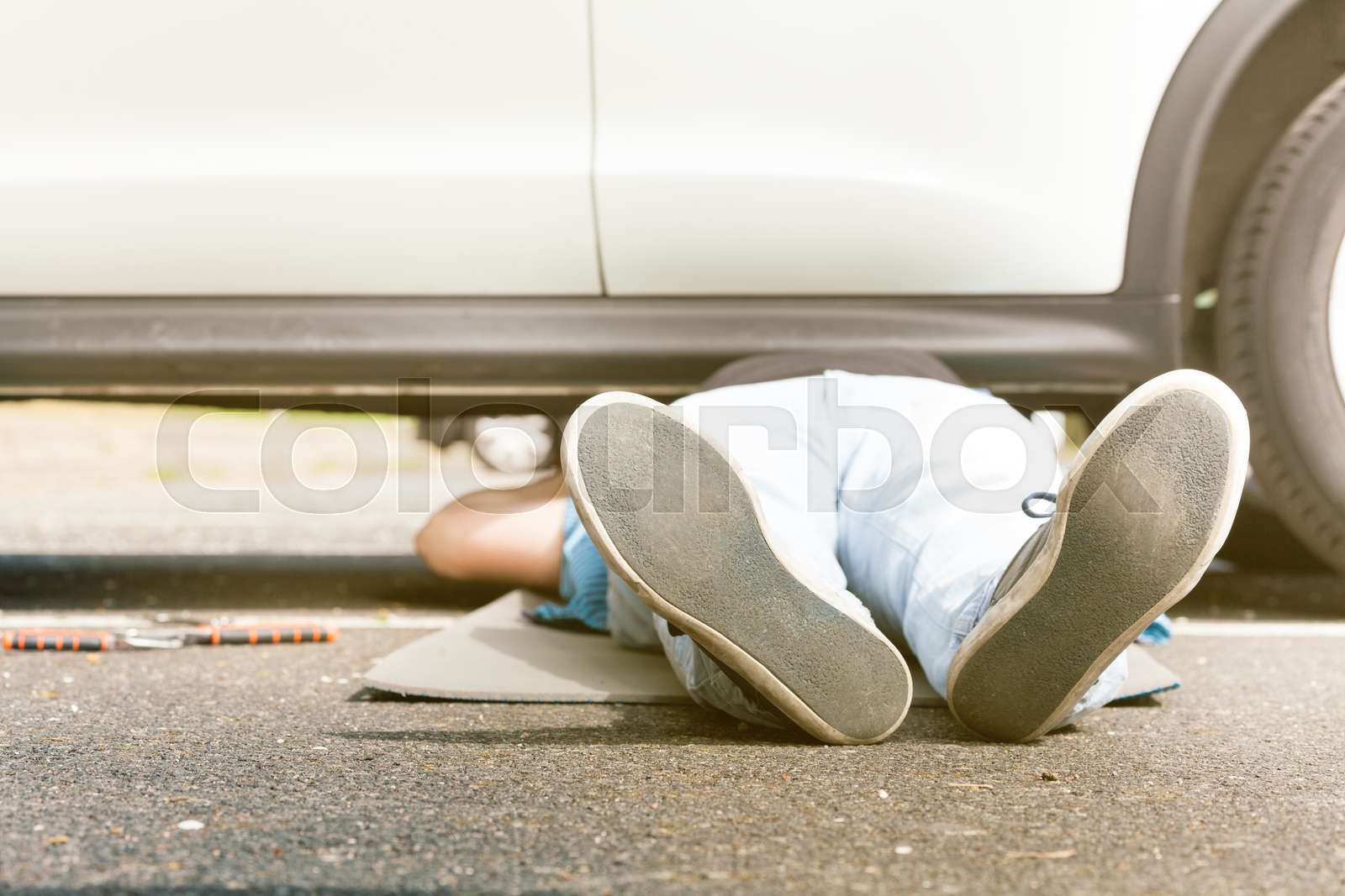 Man working under broken car outside | Stock image | Colourbox