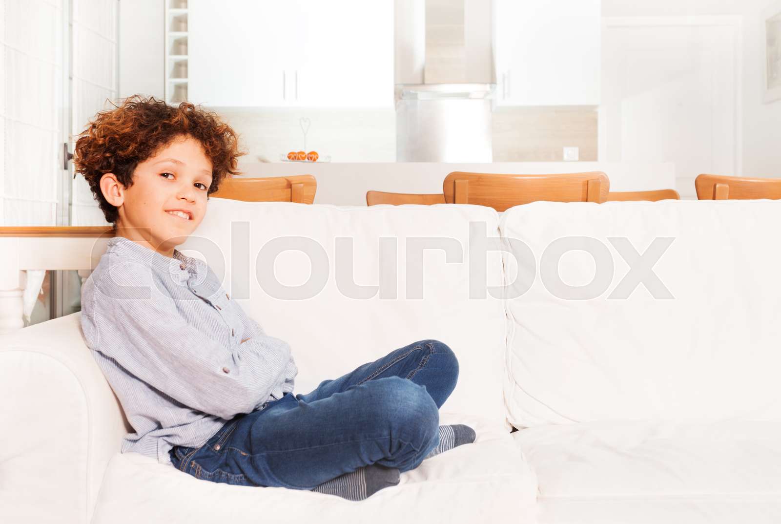 Young boy sitting on sofa in the lounge room | Stock image | Colourbox