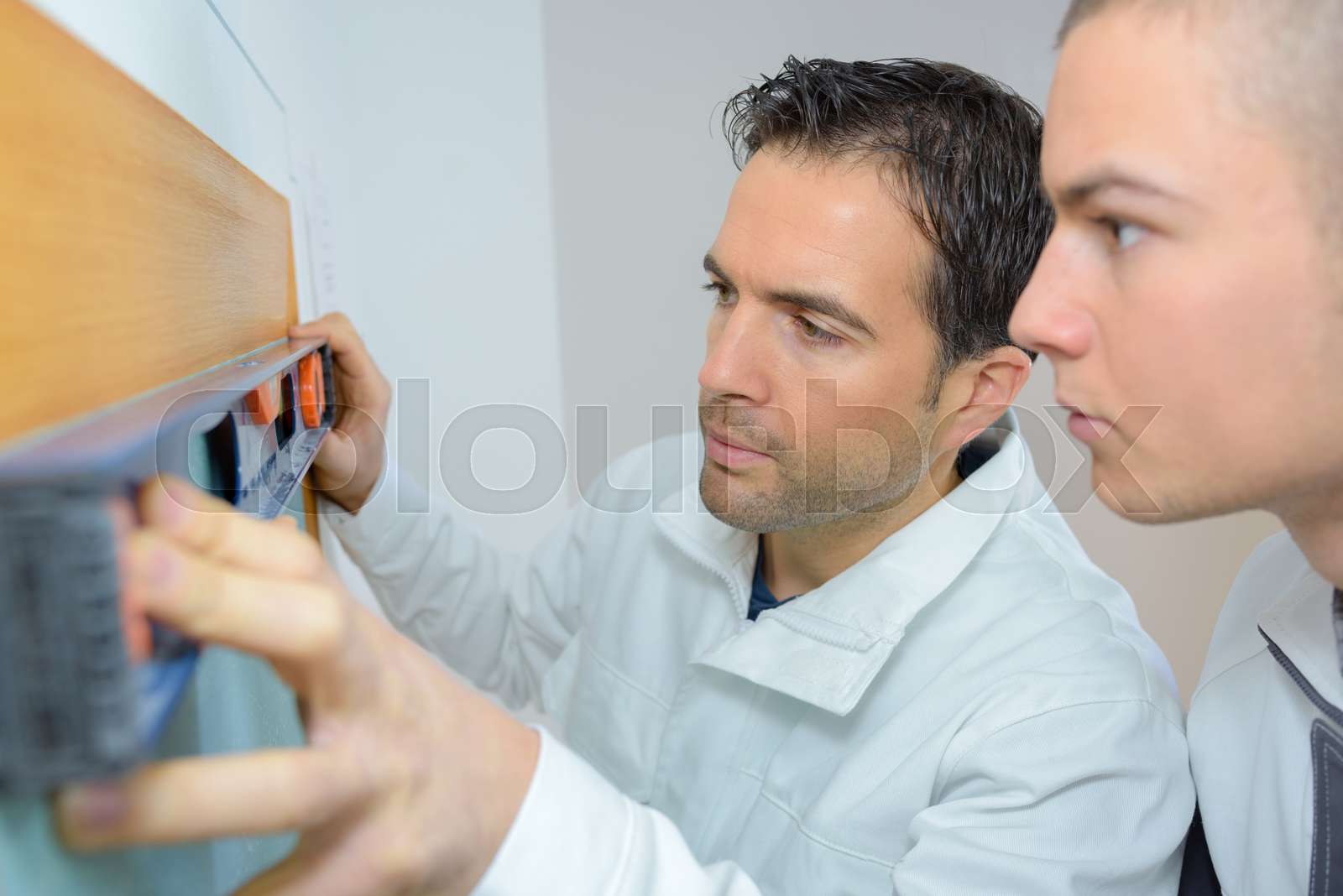 men marking on wall with level in new house | Stock image | Colourbox