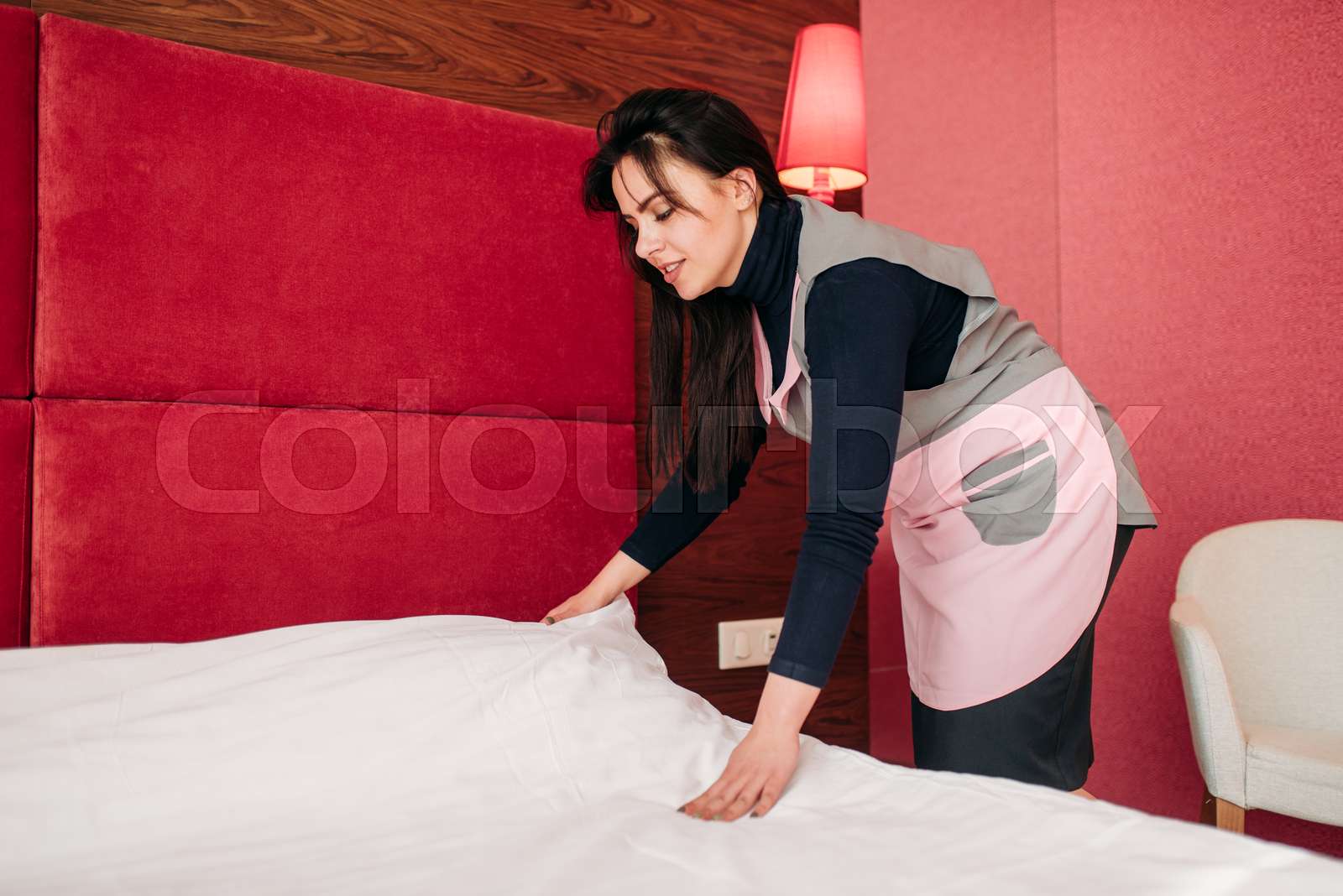 Pretty maid makes the bed in the hotel room | Stock image | Colourbox