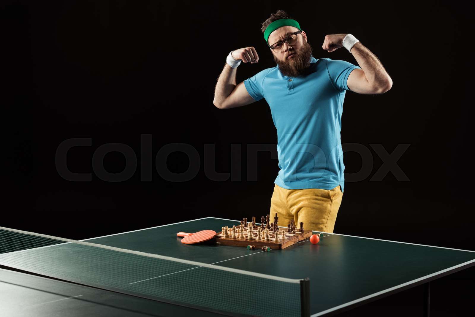 tennis player showing muscles while standing at tennis table with chess ...