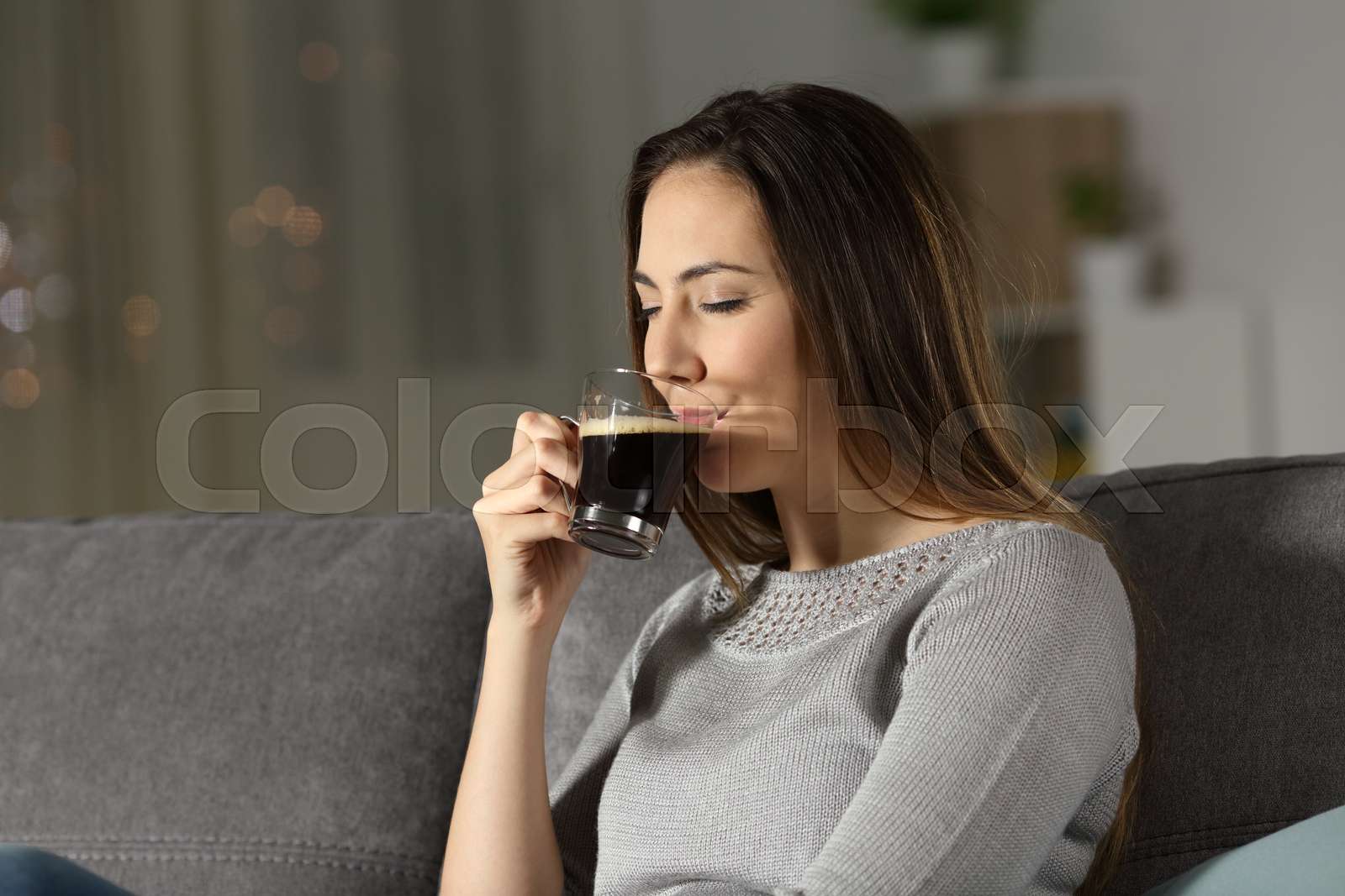 Lady drinking coffee at home in the night | Stock image | Colourbox