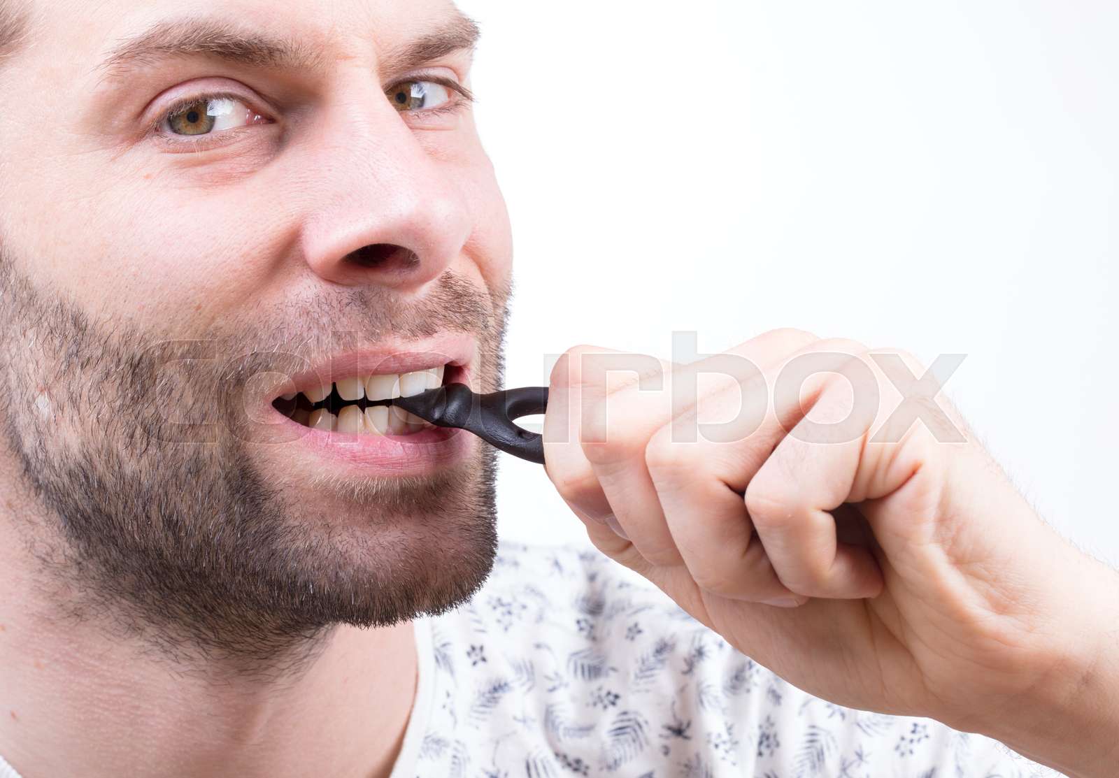 Man eating typicaly dutch candy called 'Dropsleutel' (candy key ...