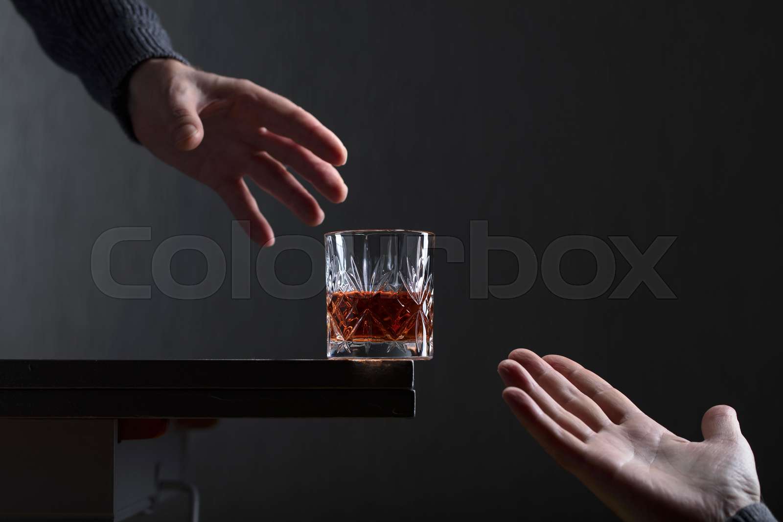 Man's hand reaches for a glass of alcohol. | Stock image | Colourbox