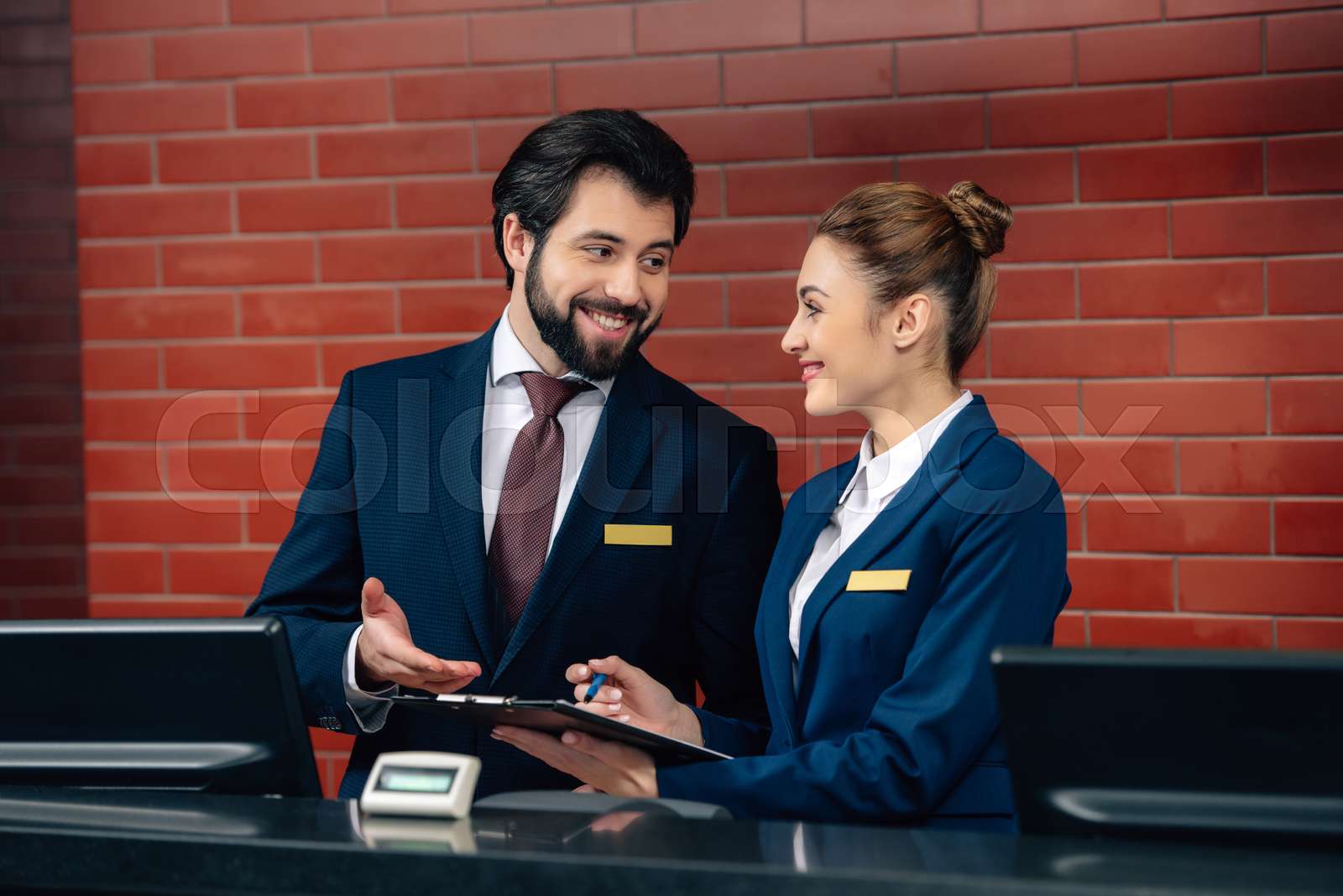 smiling hotel receptionists working together at counter | Stock image ...