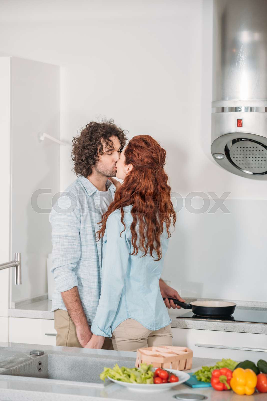 boyfriend cooking omelet and kissing girlfriend | Stock image | Colourbox