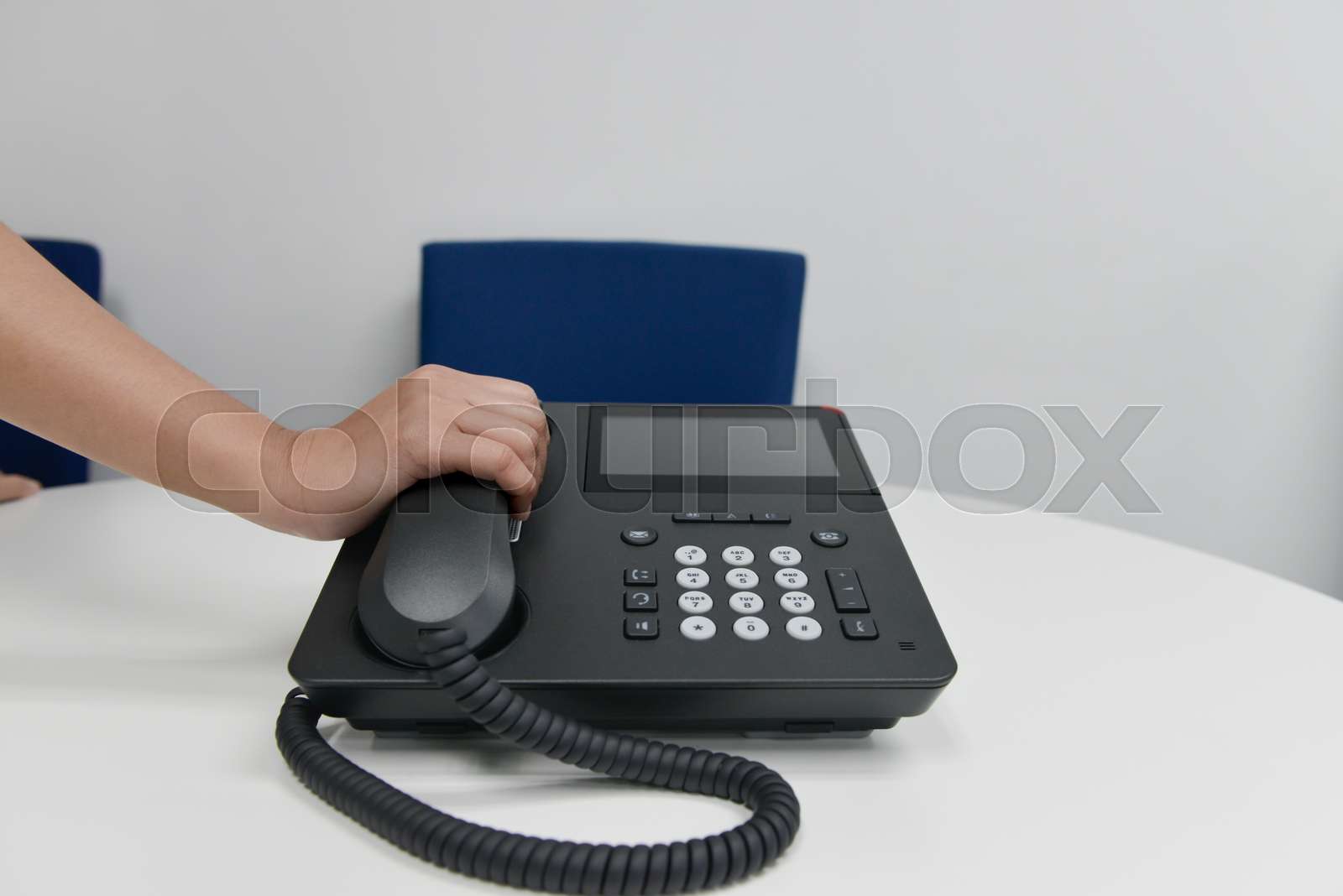 Business woman hand is holding the IP phone hand set to answer the call ...