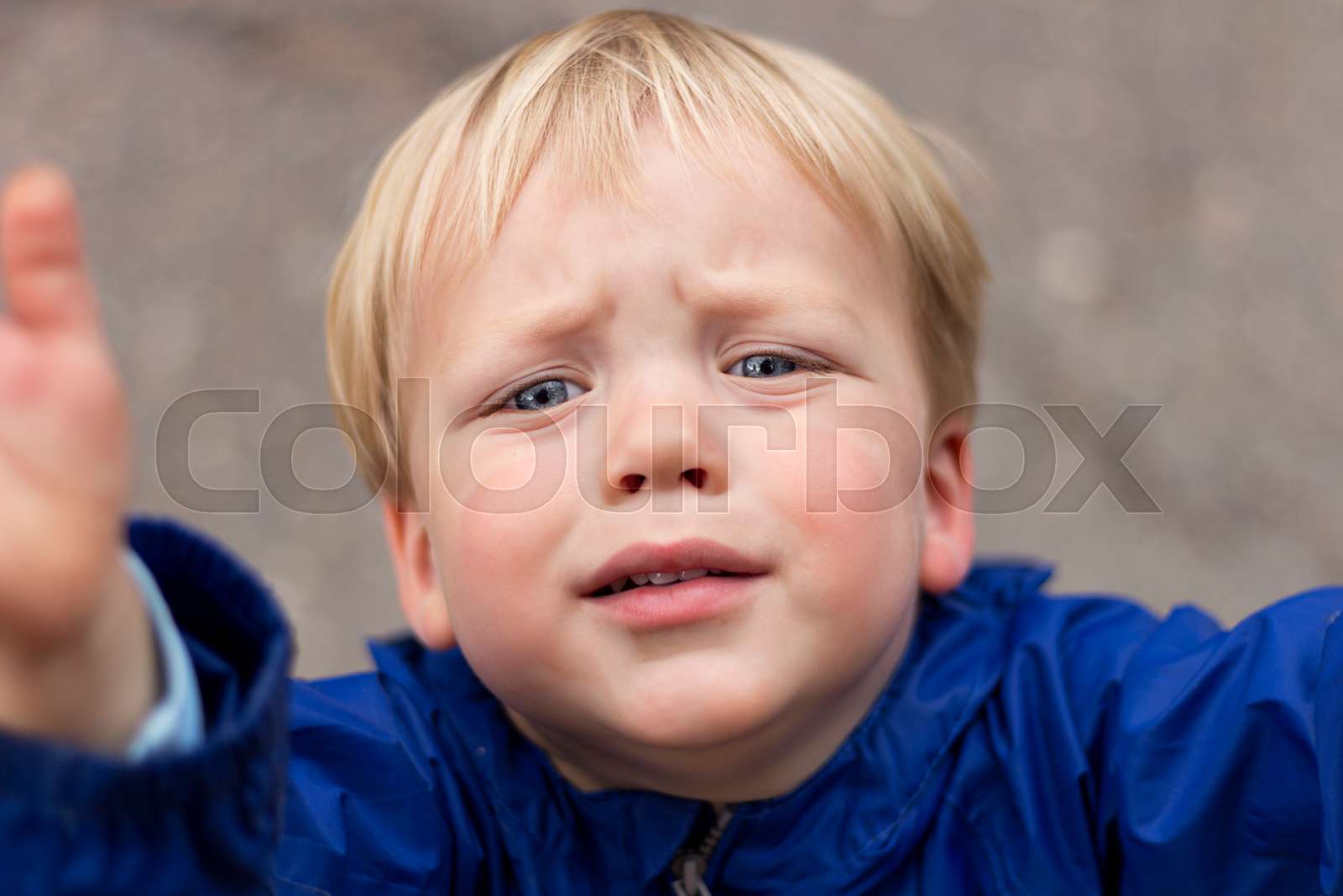 Sad crying toddler pulls his hands up. Close up portrait of baby boy ...