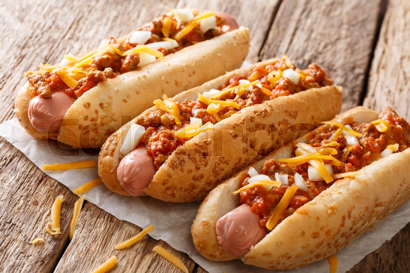 Traditional American chili hot dogs with cheddar cheese, onion and ...
