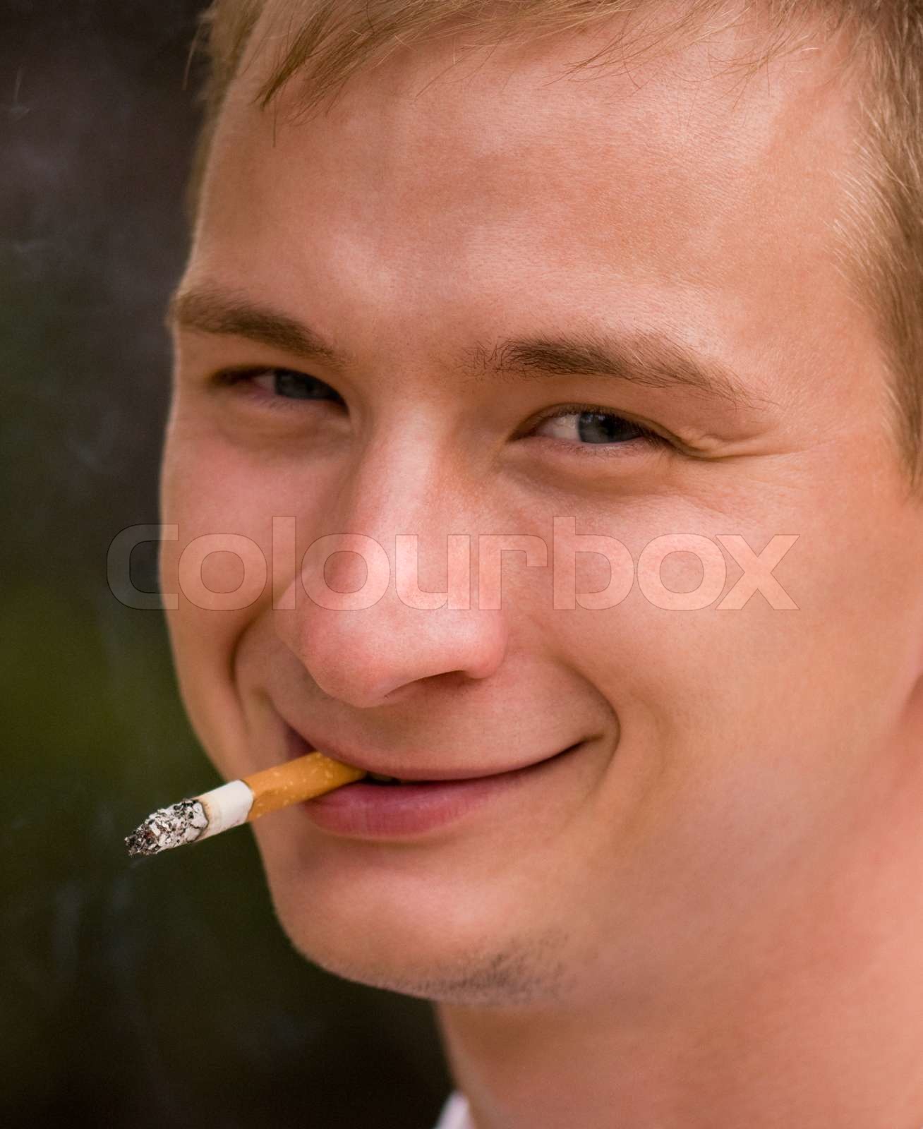 Ein junger Mann Zigarette rauchen , Fokus ist auf sein Gesicht gesetzt ...