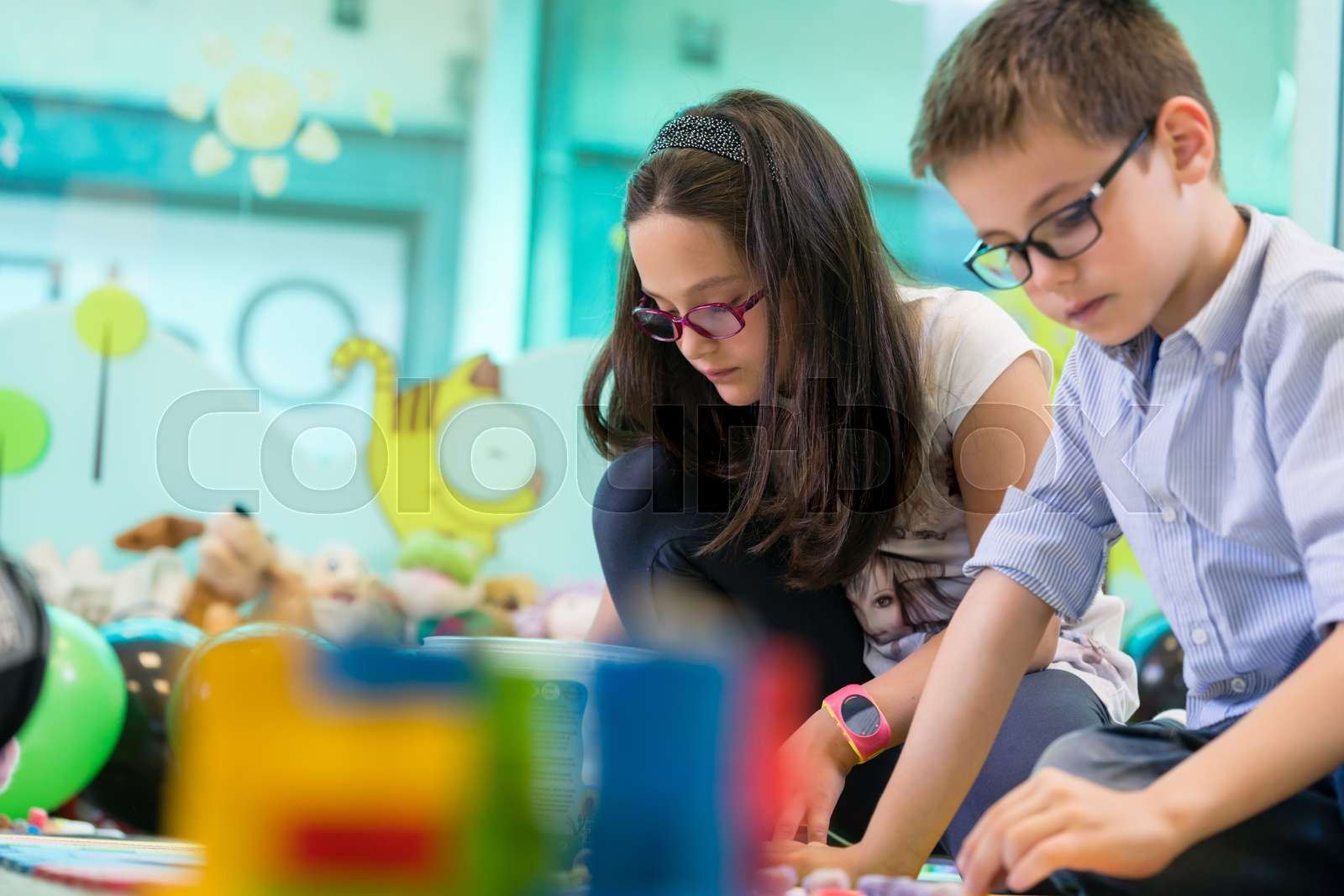 Cute girl playing next to her classmate in a modern kindergarten ...