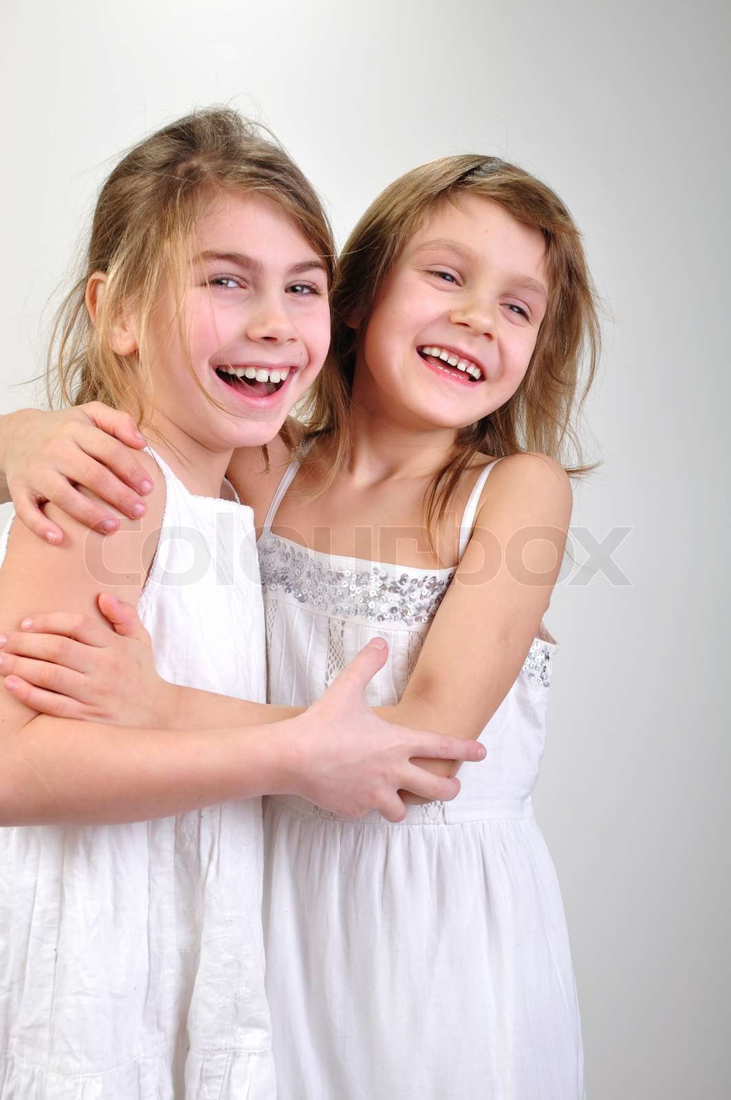 Studio portrait of two laughing hugging girls | Stock image | Colourbox