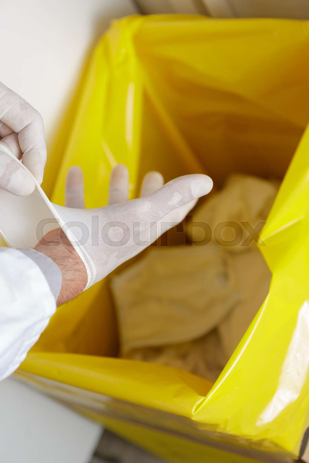 healthcare professional throwing away disposable latex gloves in trash ...