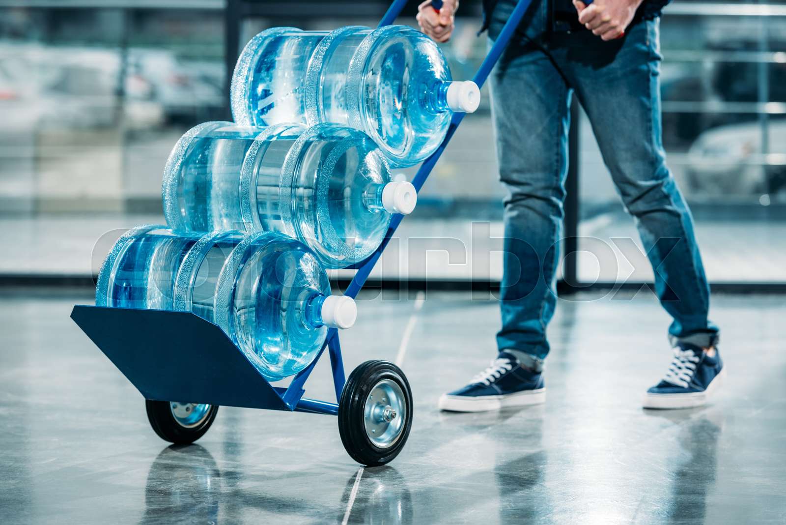 Loader pushing cart with water bottles | Stock image | Colourbox