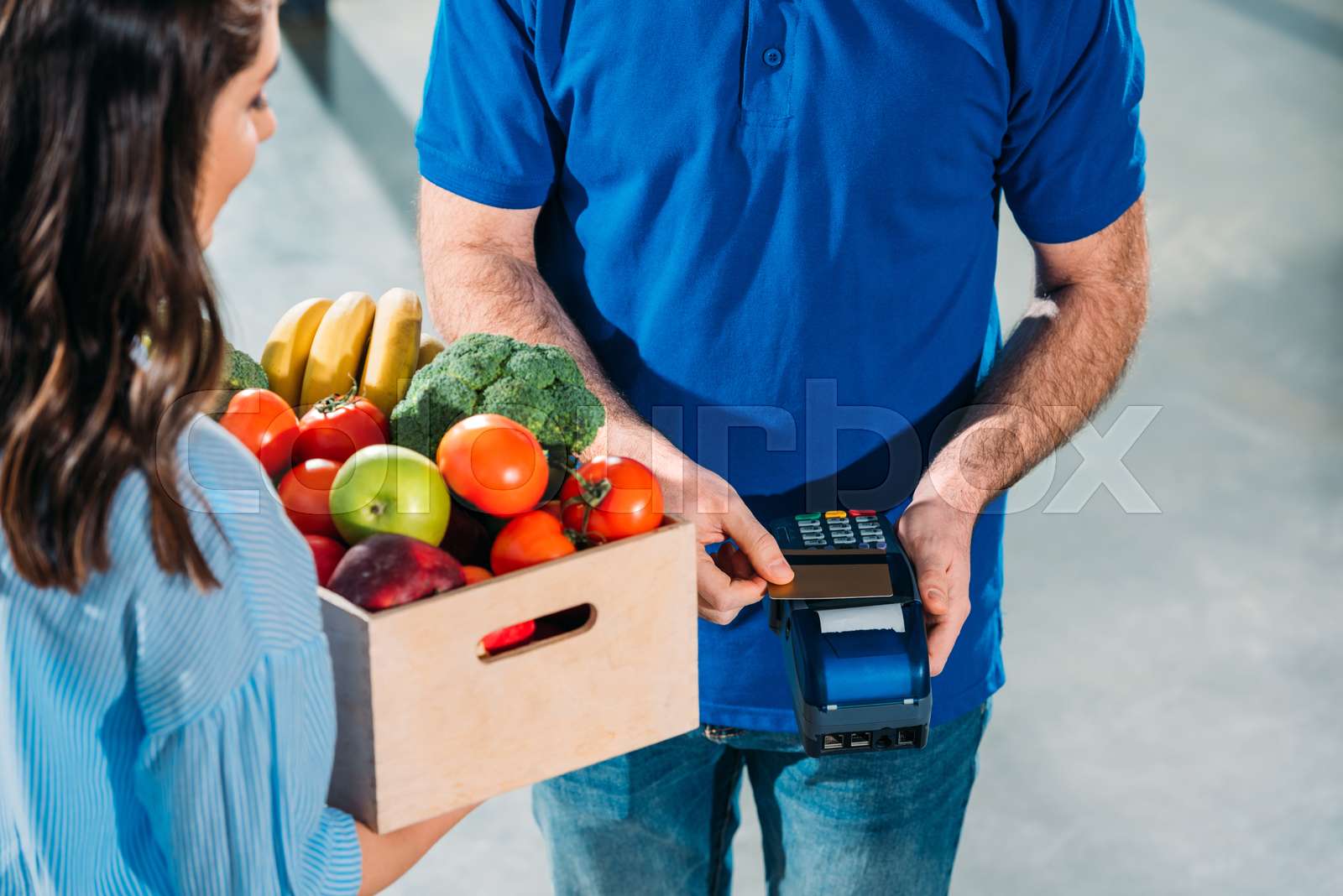 Delivery man using card and payment terminal while woman holding ...