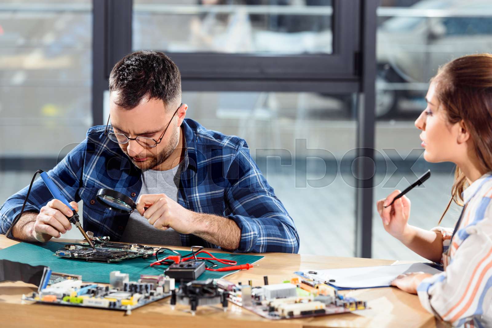 Woman filling checklist while engineer soldering computer parts | Stock ...