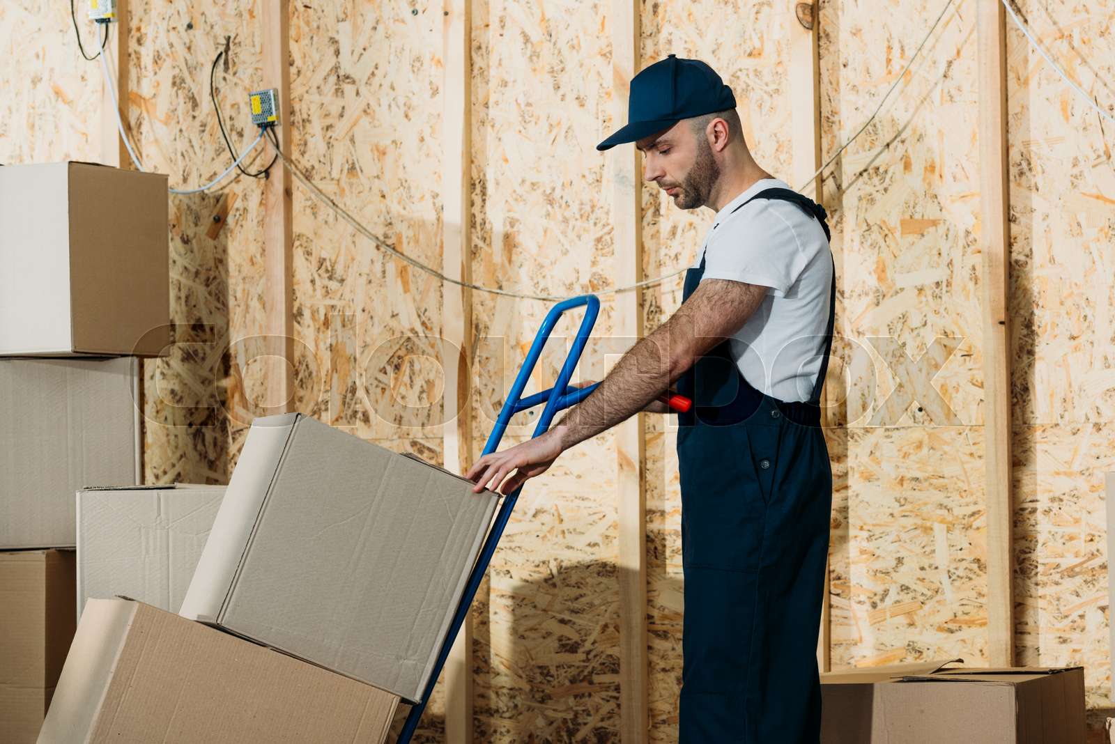 Loader man adjusting cardboard boxes on delivery cart | Stock image ...