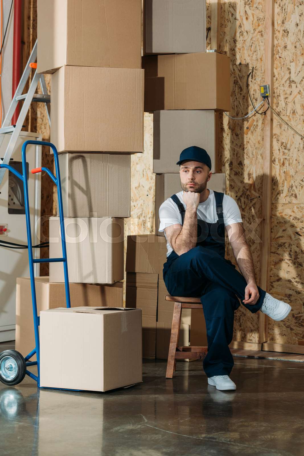 Resting delivery man sitting by stacks of boxes | Stock image | Colourbox