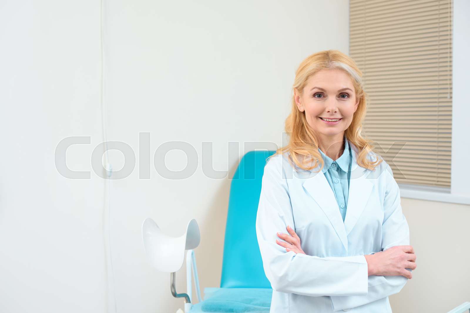 mature female gynecologist with crossed arms in front of gynecology ...