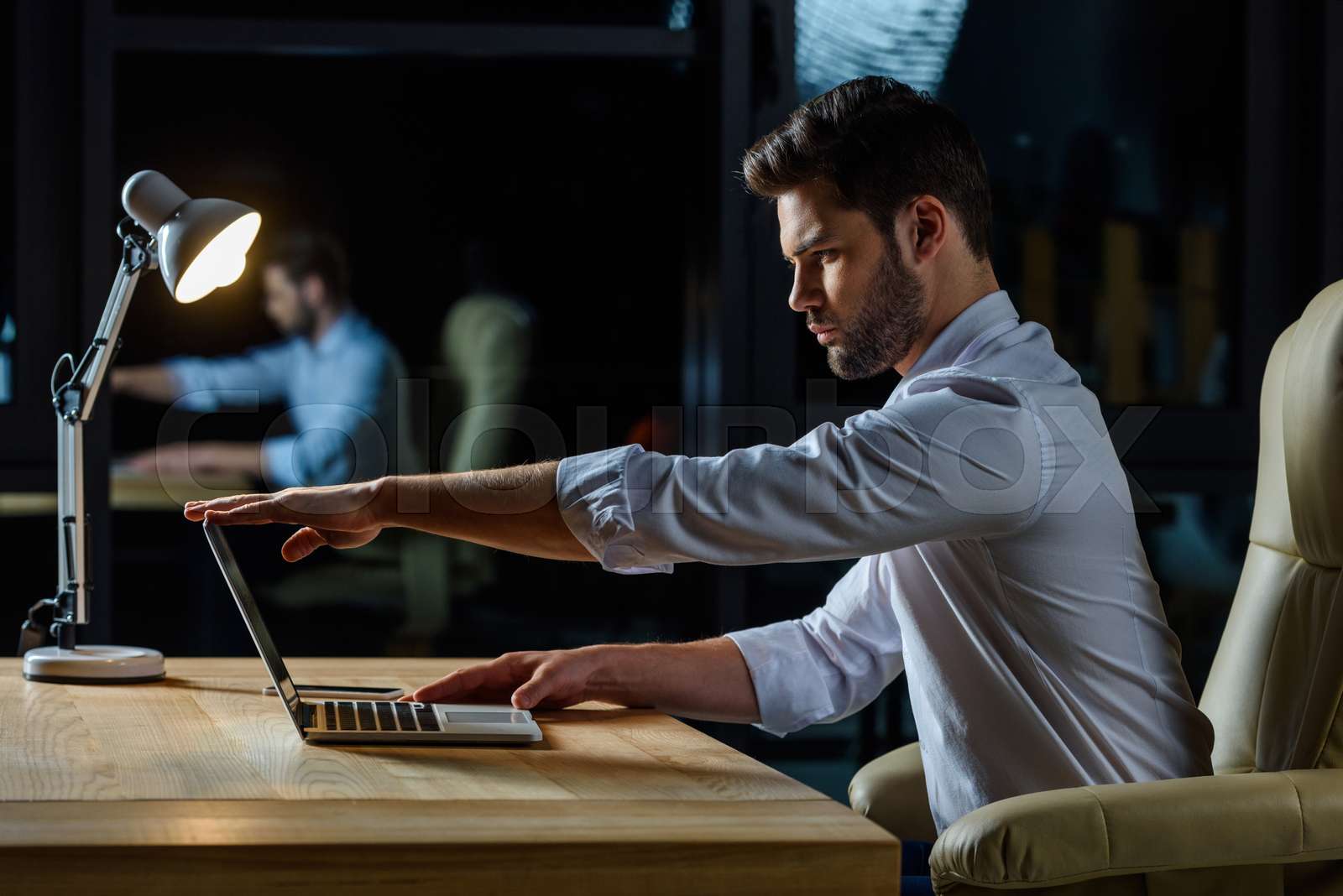 side view of businessman opening laptop at table | Stock image | Colourbox