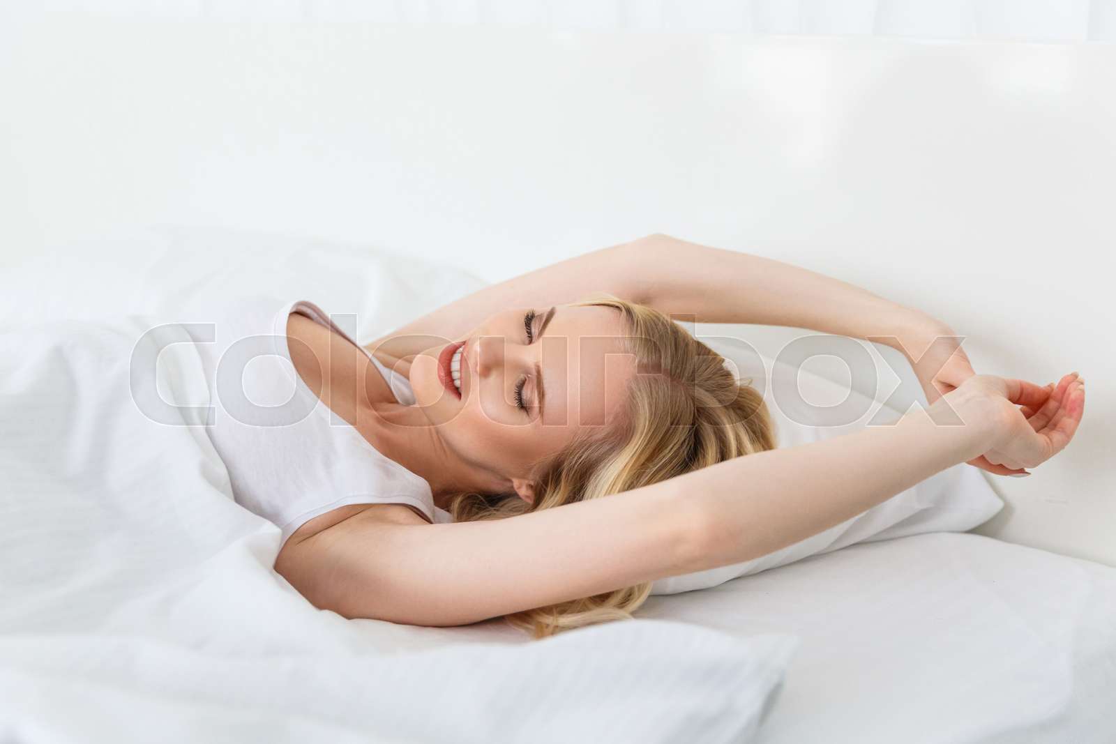 beautiful smiling blonde girl stretching in bed | Stock image | Colourbox