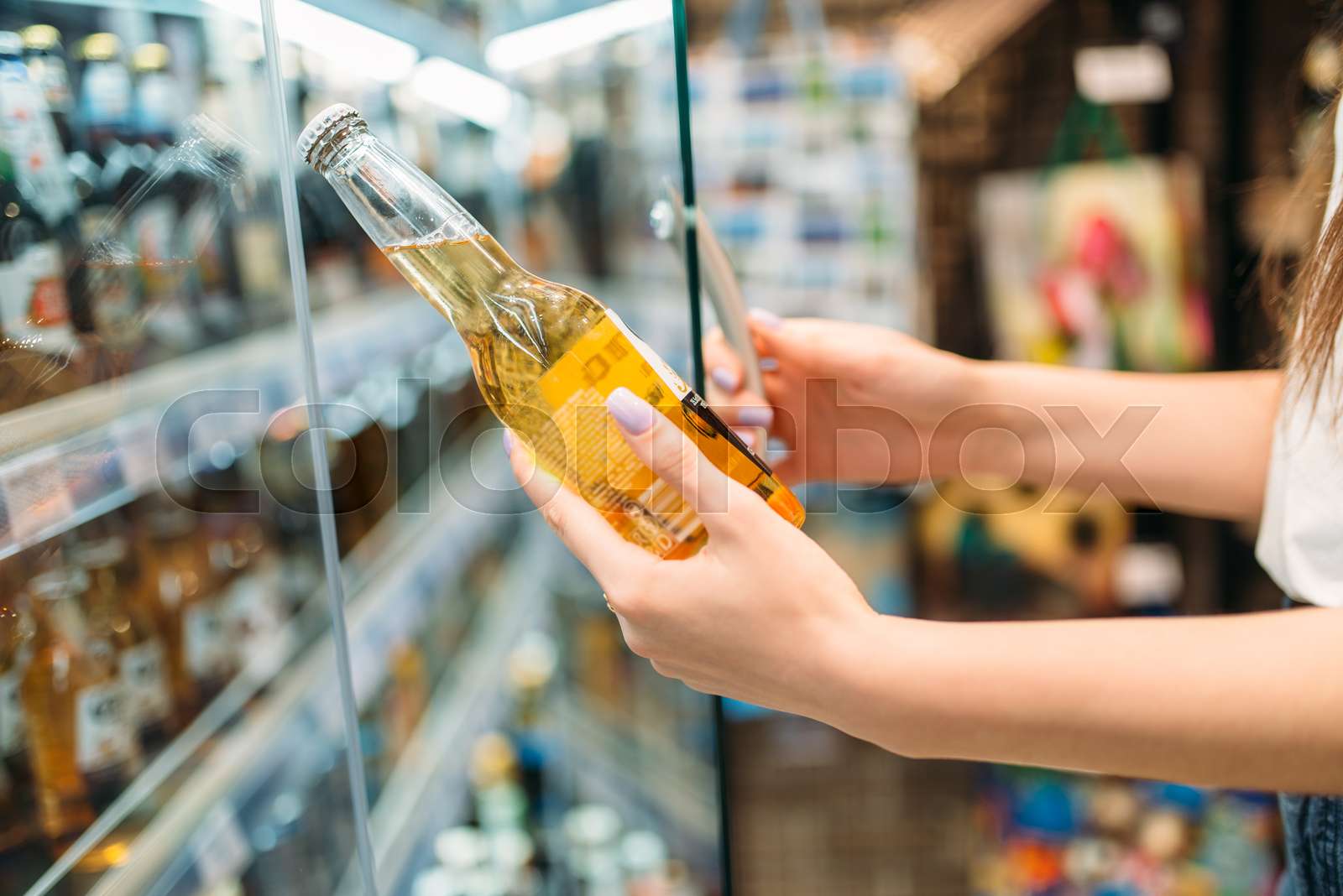 Female buyer choosing a beer in supermarket | Stock image | Colourbox