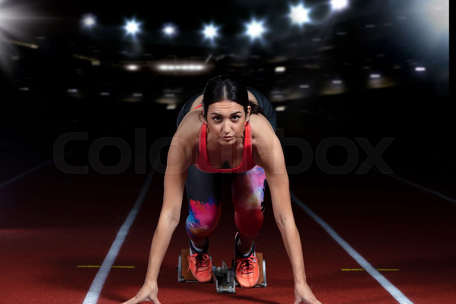 woman sprinter leaving starting blocks on the athletic track. exploding ...