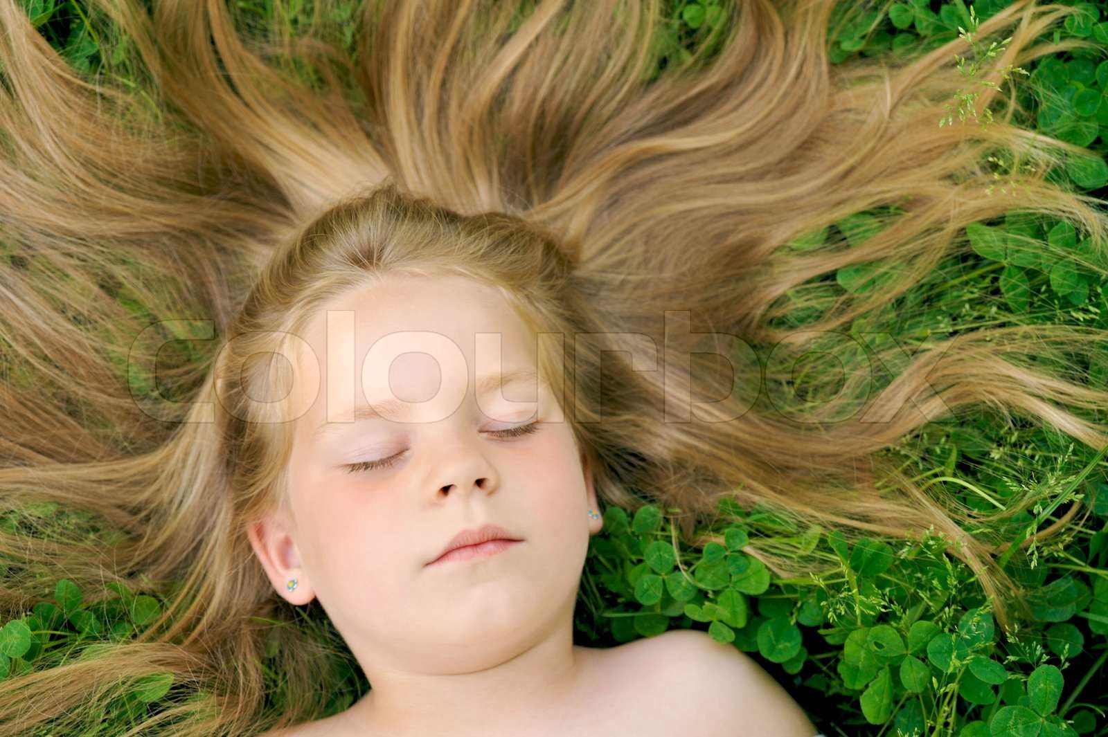 Little girl sunbathing – sleeping on grass | Stock image | Colourbox