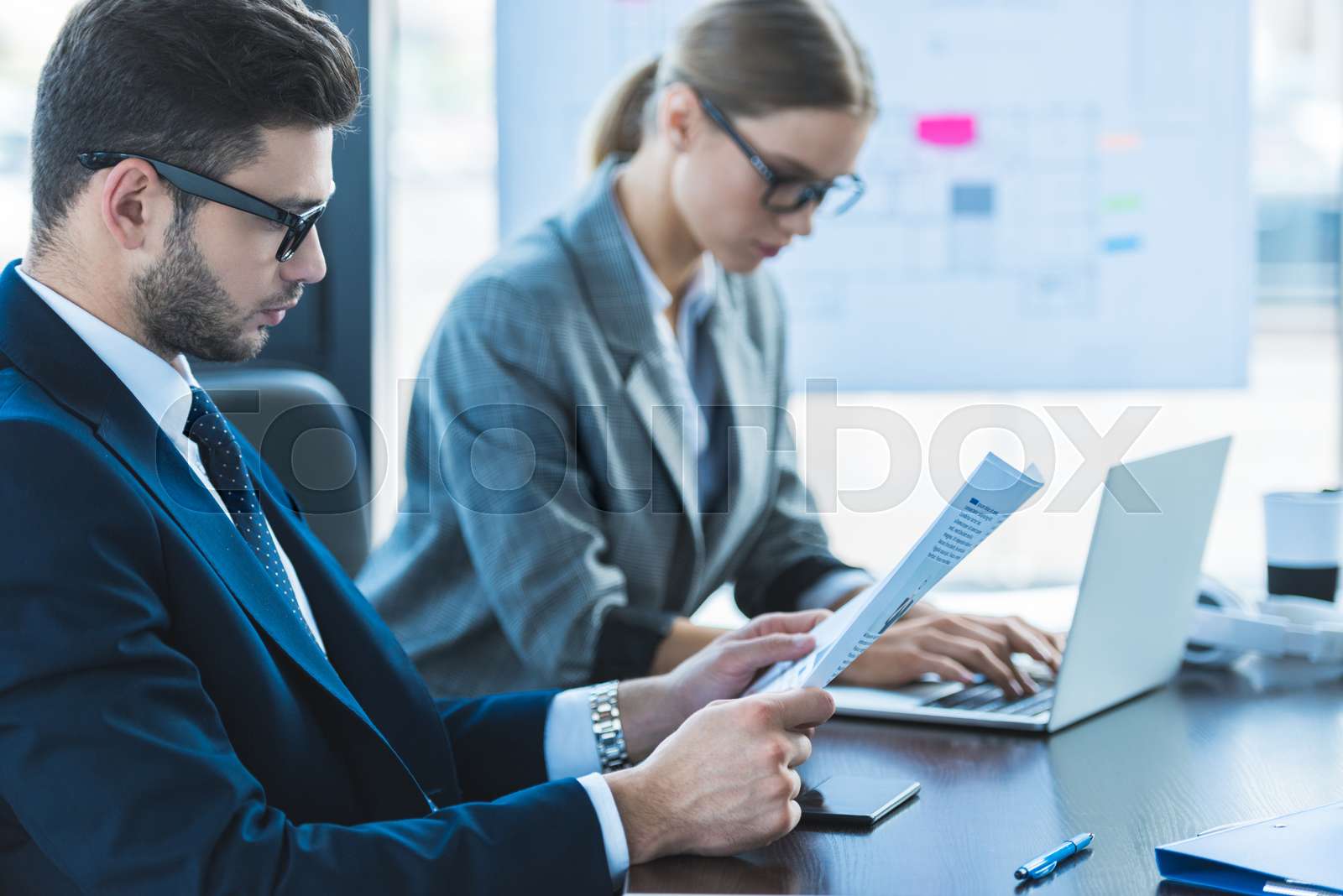 side view of businessman and businesswoman looking at documents in ...