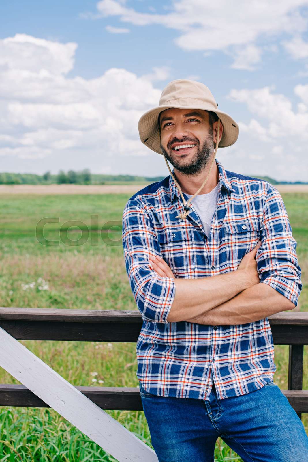 happy middle aged farmer standing with crossed arms and looking away at ...