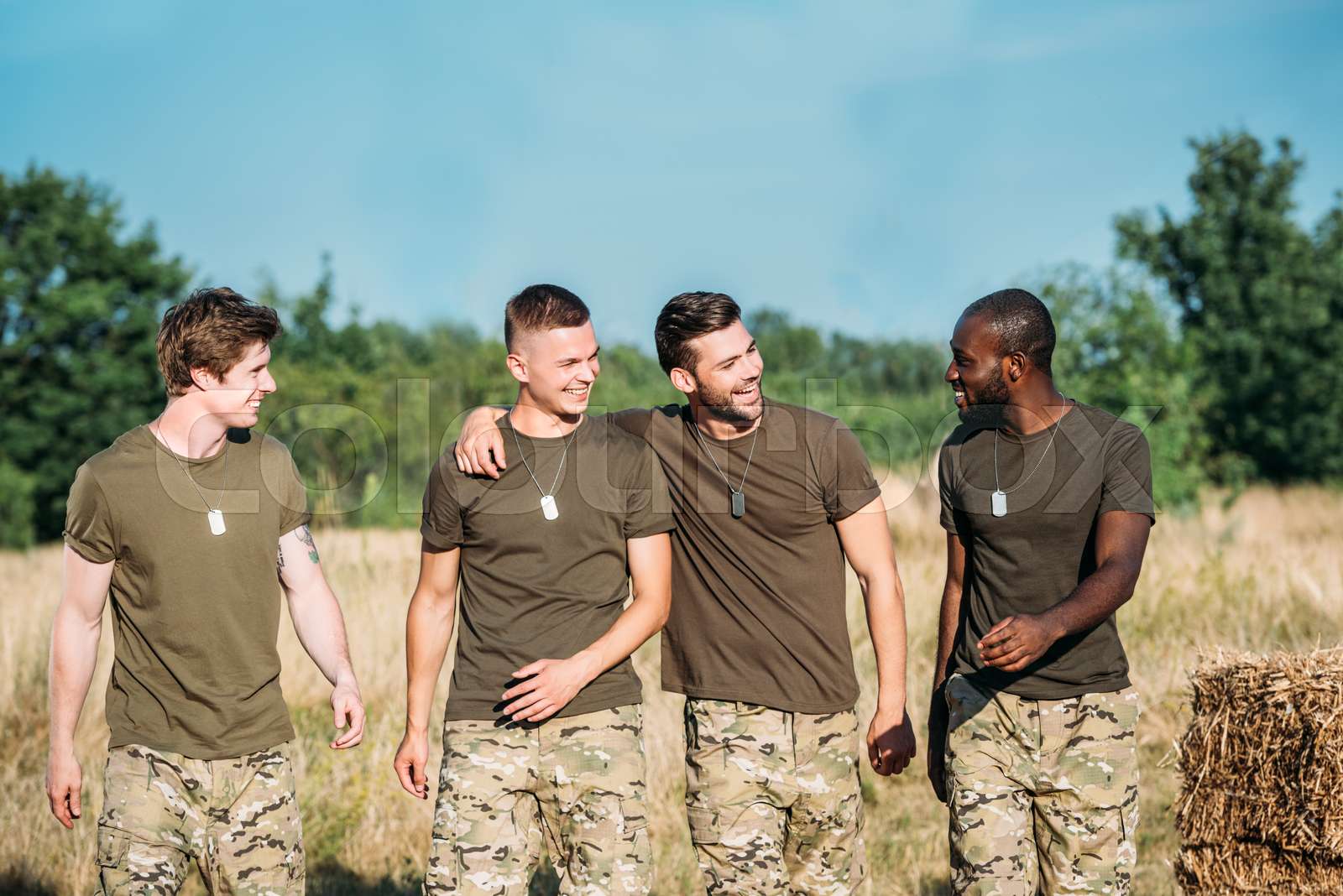 portrait of multicultural smiling soldiers in military uniform on range ...