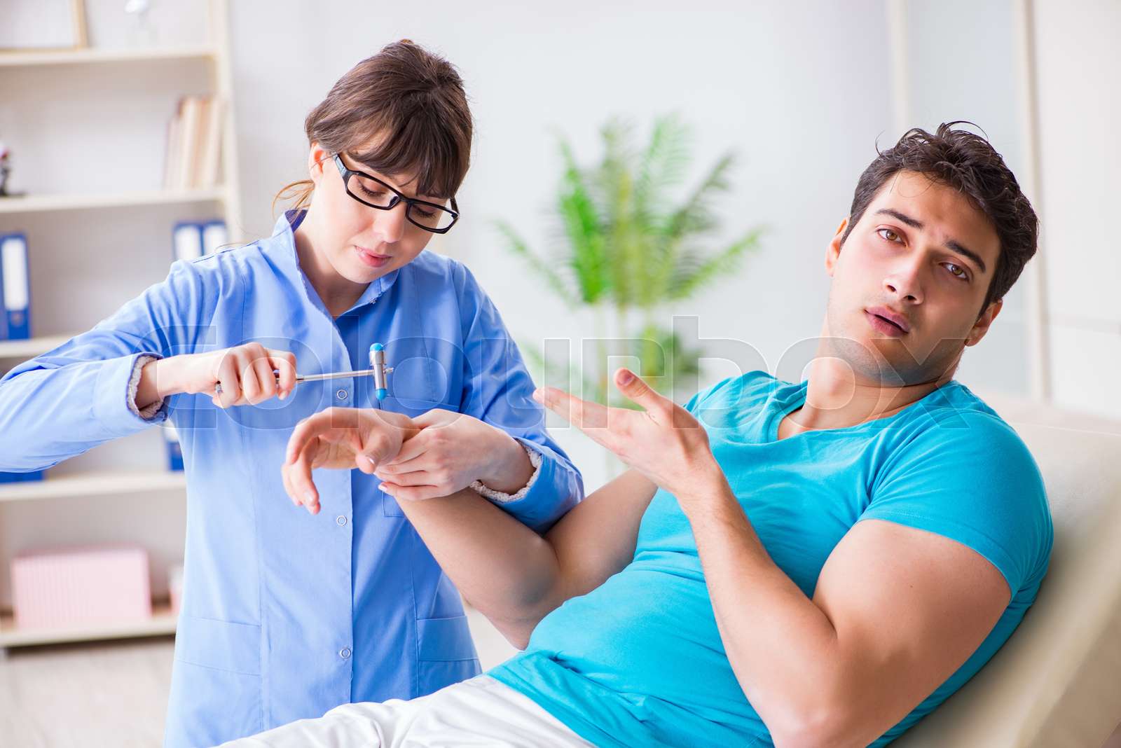 Doctor checking nerve reflexes with hammer | Stock image | Colourbox