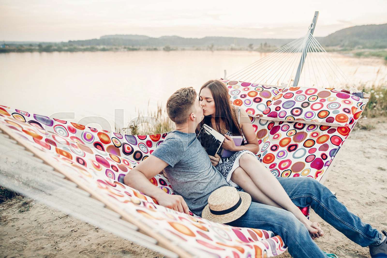 Happy couple kissing on the beach at sunset, romantic husband and wife ...