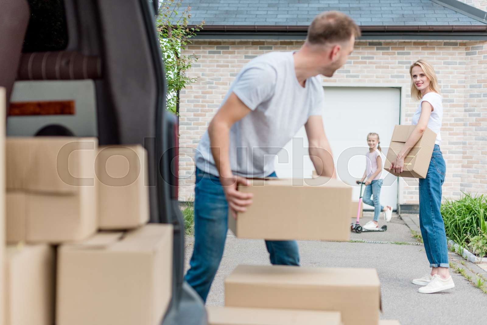 young couple carrying cardboard boxes for relocation into new house and ...